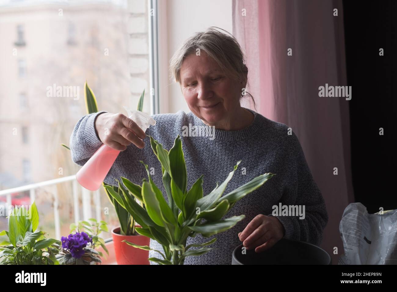 Woman Taking Care Of Plants Spraying A Plant With Pure Water From A