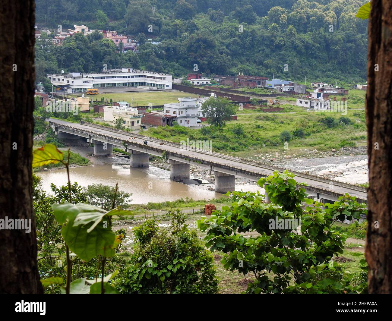 A wide-angle shot of a concrete bridge built over a river with trees ...