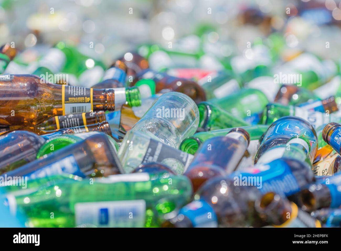 A pile or stack of empty glass bottles, clear and coloured, waiting to ...