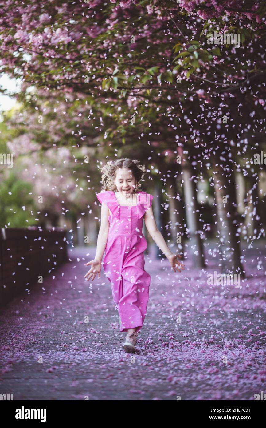 Beautiful girl in pink dress in cherry blossom park on a spring day ...