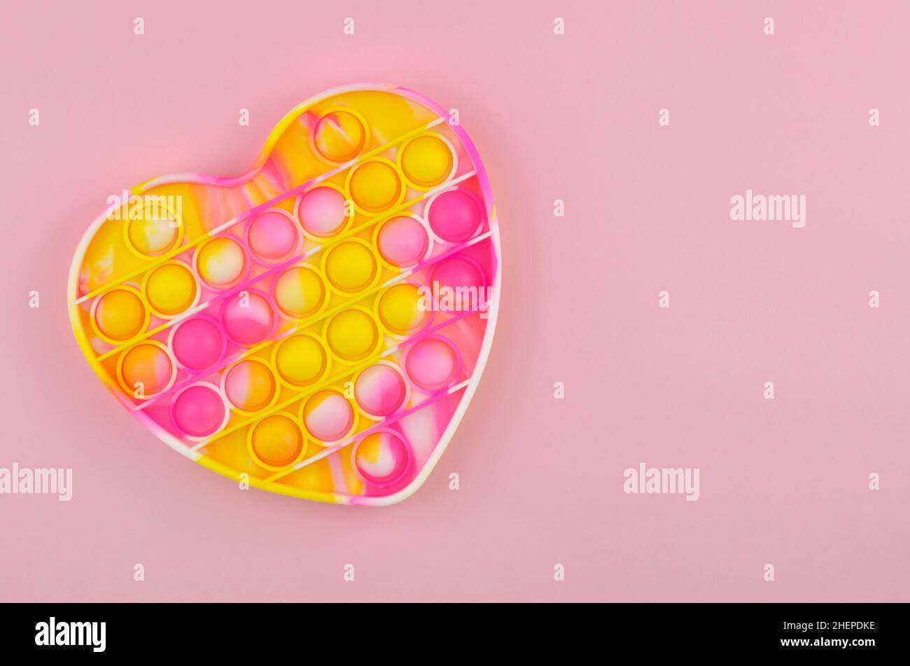 Bright silicone popular toy Pop it in the shape of a heart on a pink ...