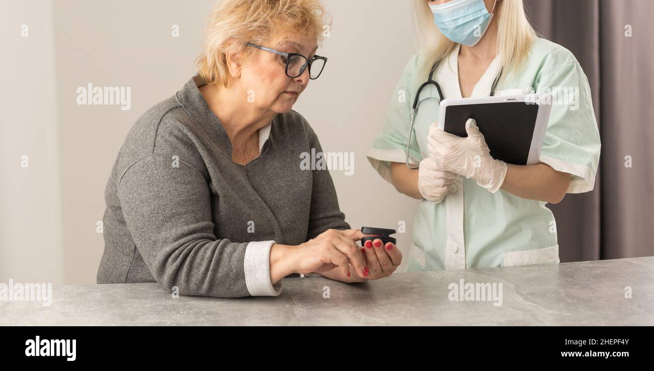 Female caregiver with fingertip pulse oximeter,attached on finger of ...