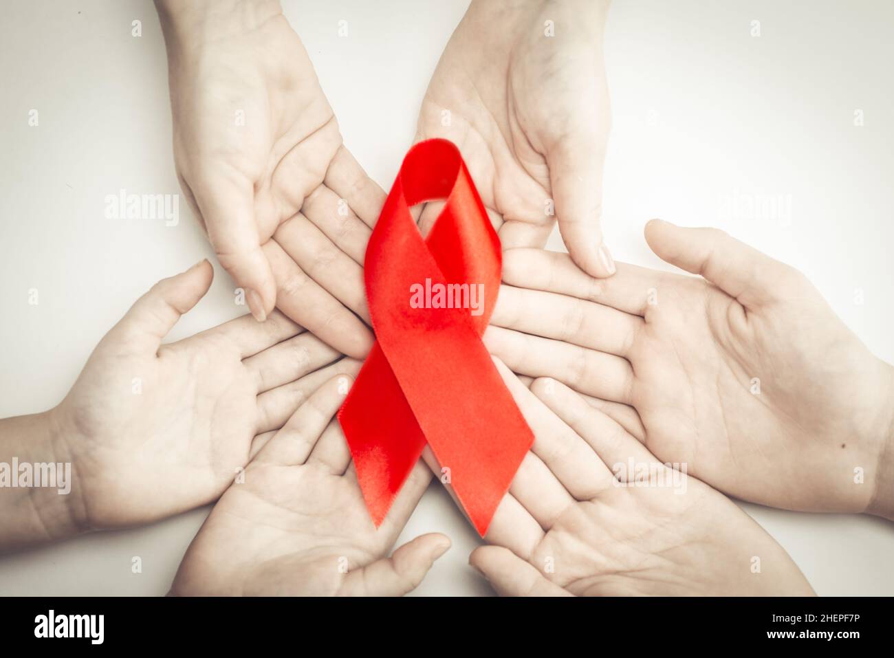 Health care and medicine concept. AIDS awareness. Many people's hands are holding a large red ...