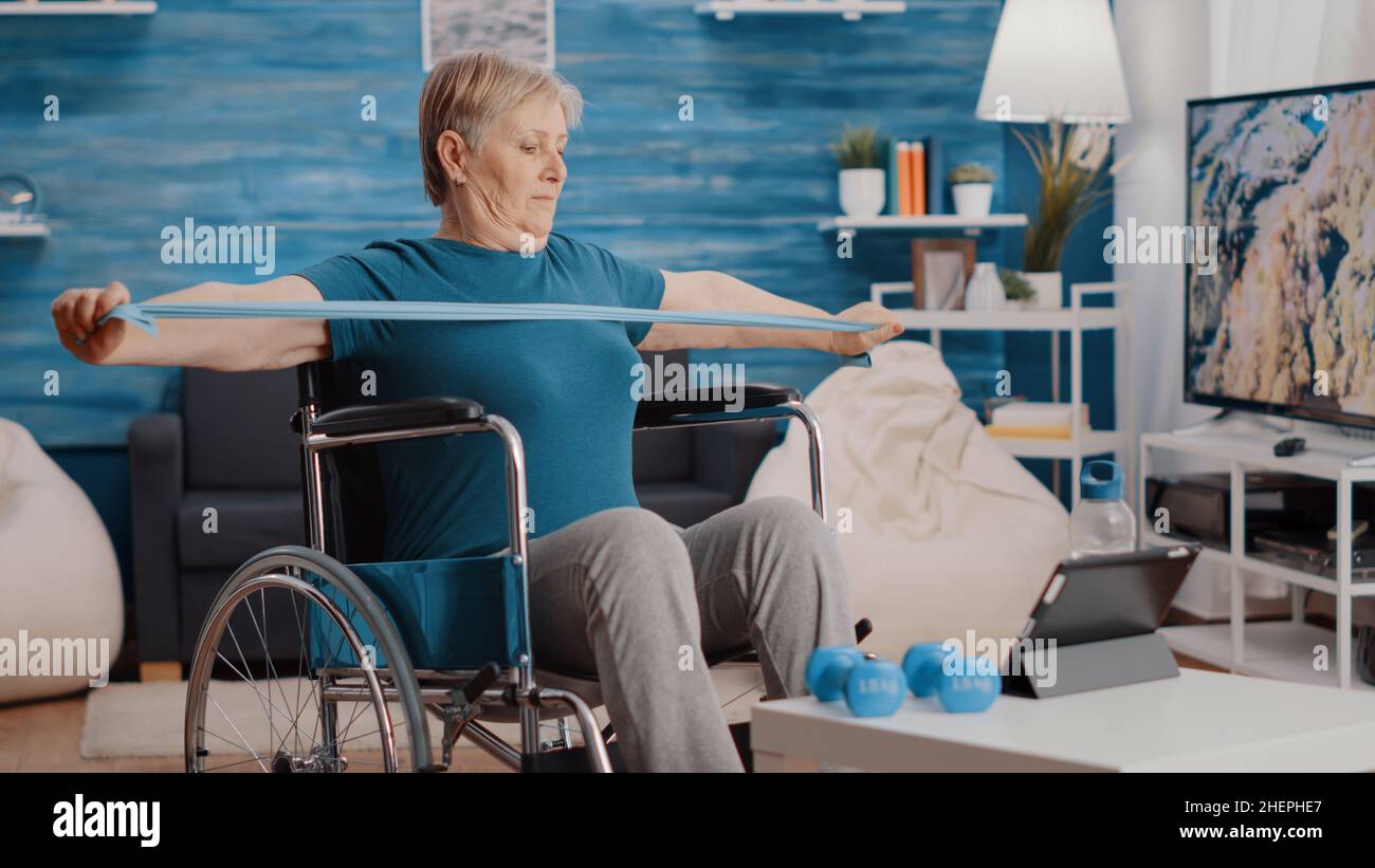 Elder person with disability stretching resistance band and following ...