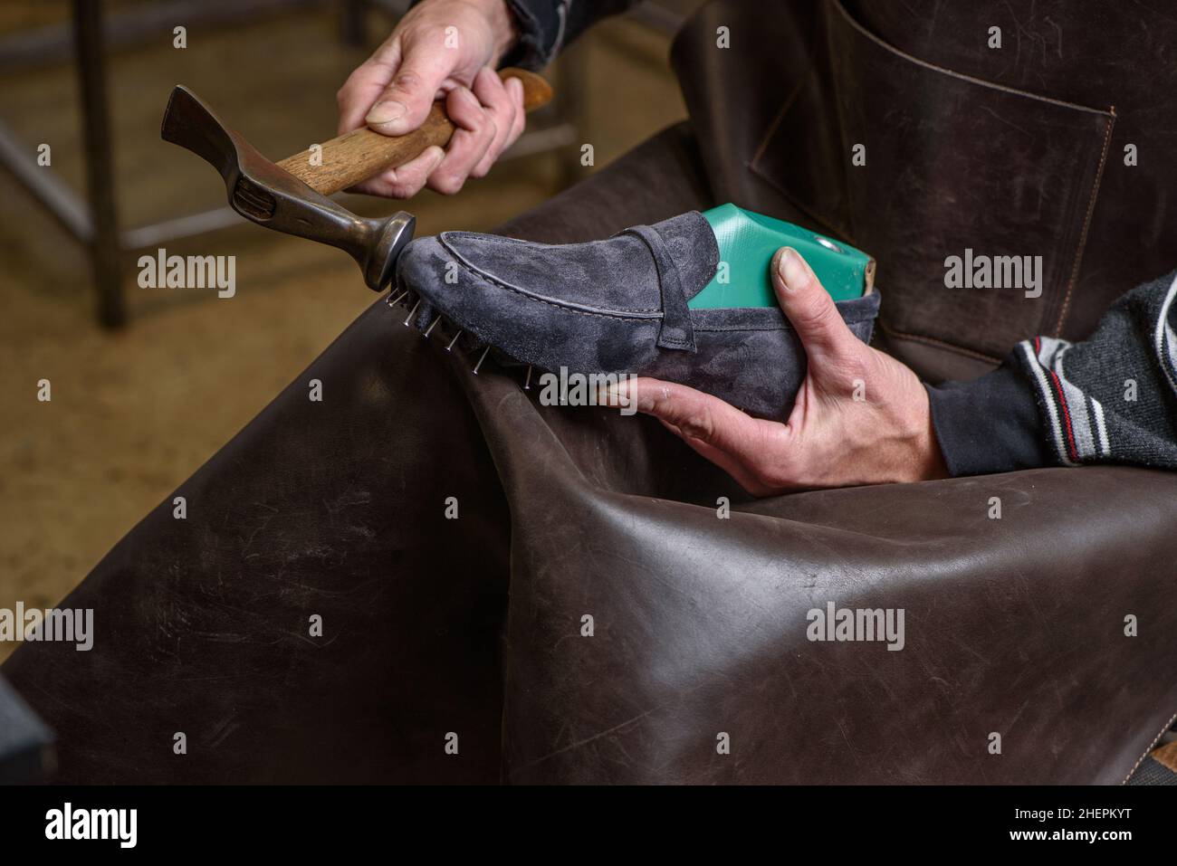 Shoemaker in leather apron making shoes in workshop. Male hands holding ...