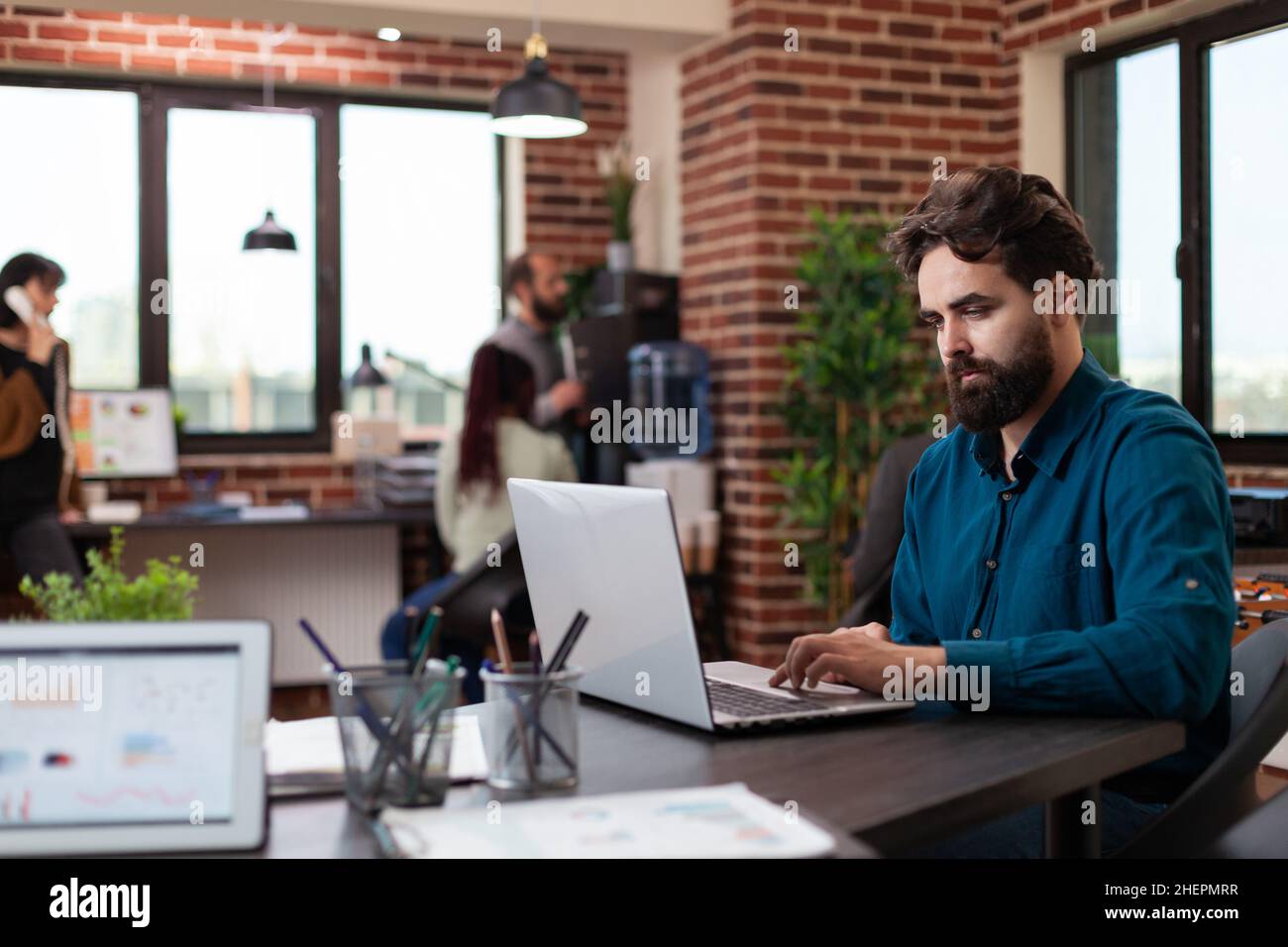 Businessman sitting at desk typing marketing strategy on laptop ...