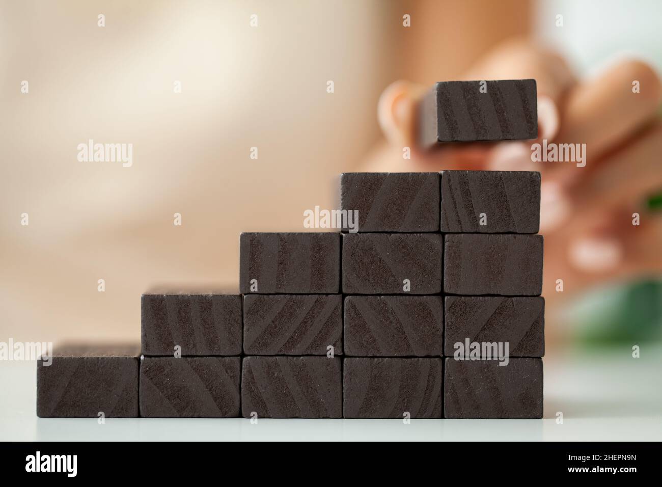 Hand putting wood cube on top of wood block stacking as step stair ...