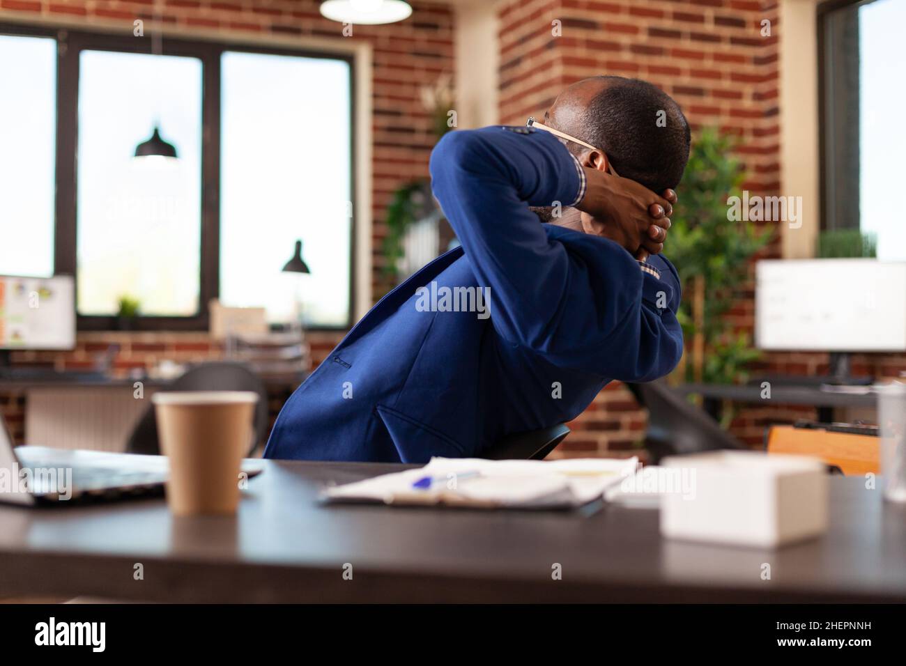 Entrepreneur sitting with hands over head to relax after finishing task ...