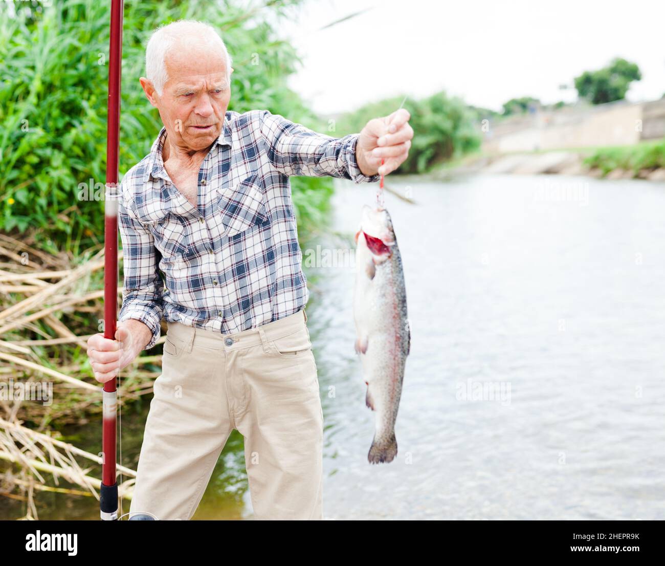 Fisherman pulling fish from river Stock Photo - Alamy