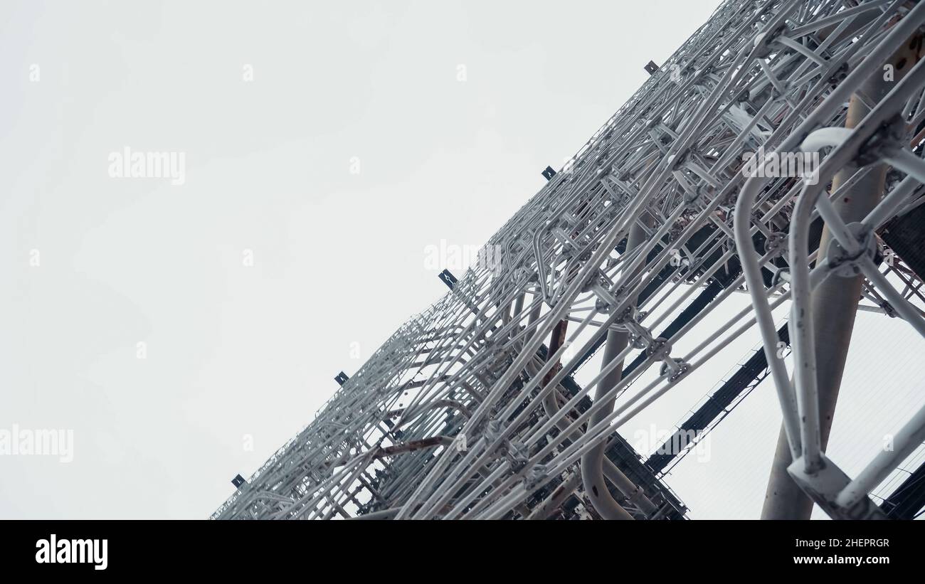 bottom view of old radar station in chernobyl zone against grey sky ...
