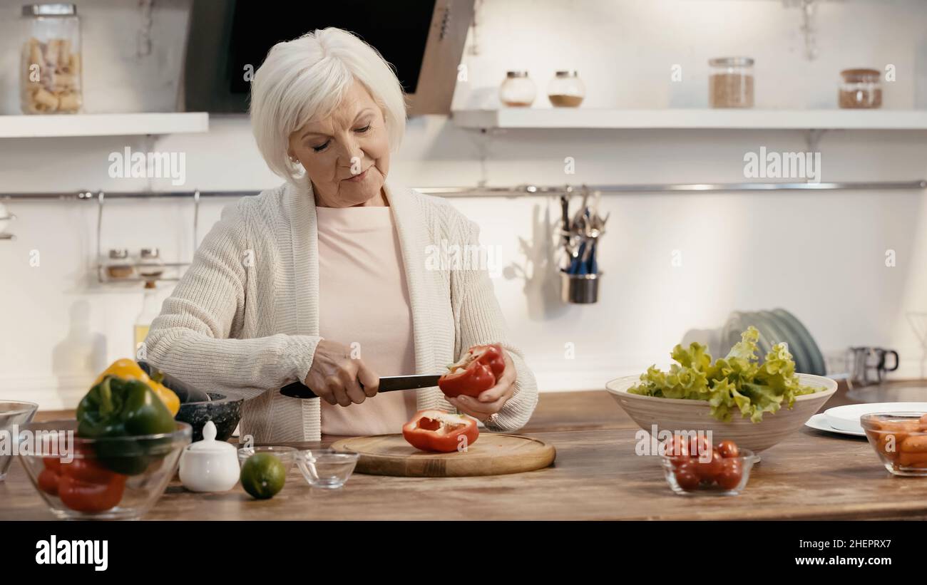 senior woman peeling bell pepper while preparing thanksgiving dinner ...