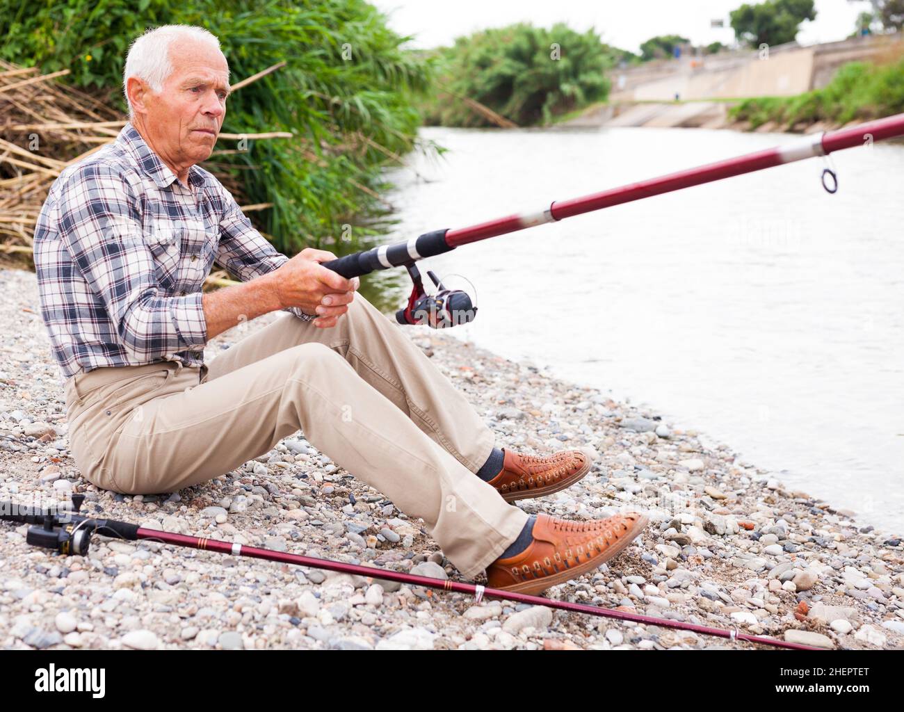 Aged man fishing at lakeside Stock Photo - Alamy