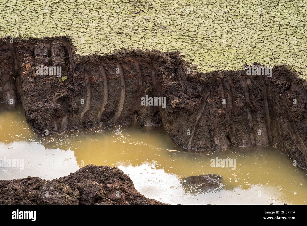 A dug trench with water in a close up against the background of a dried ...