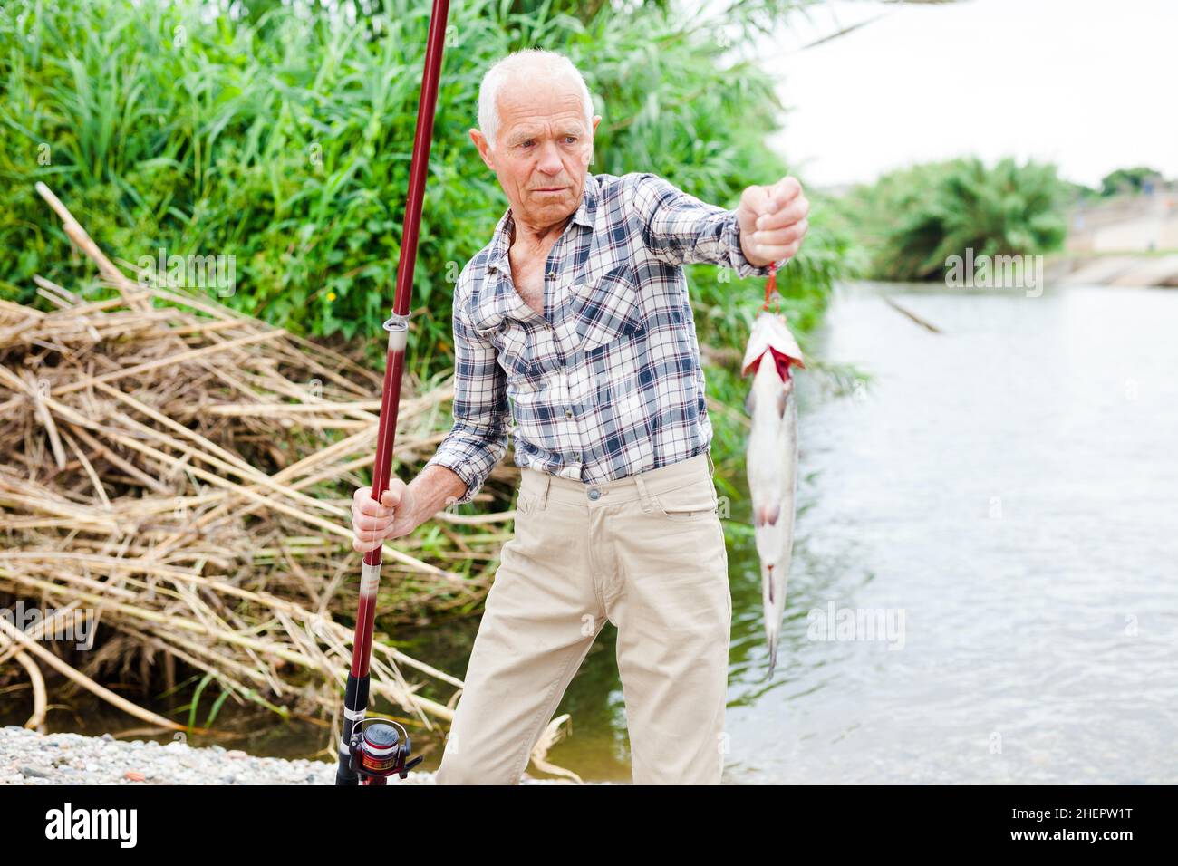 Fisherman pulling fish from river Stock Photo - Alamy