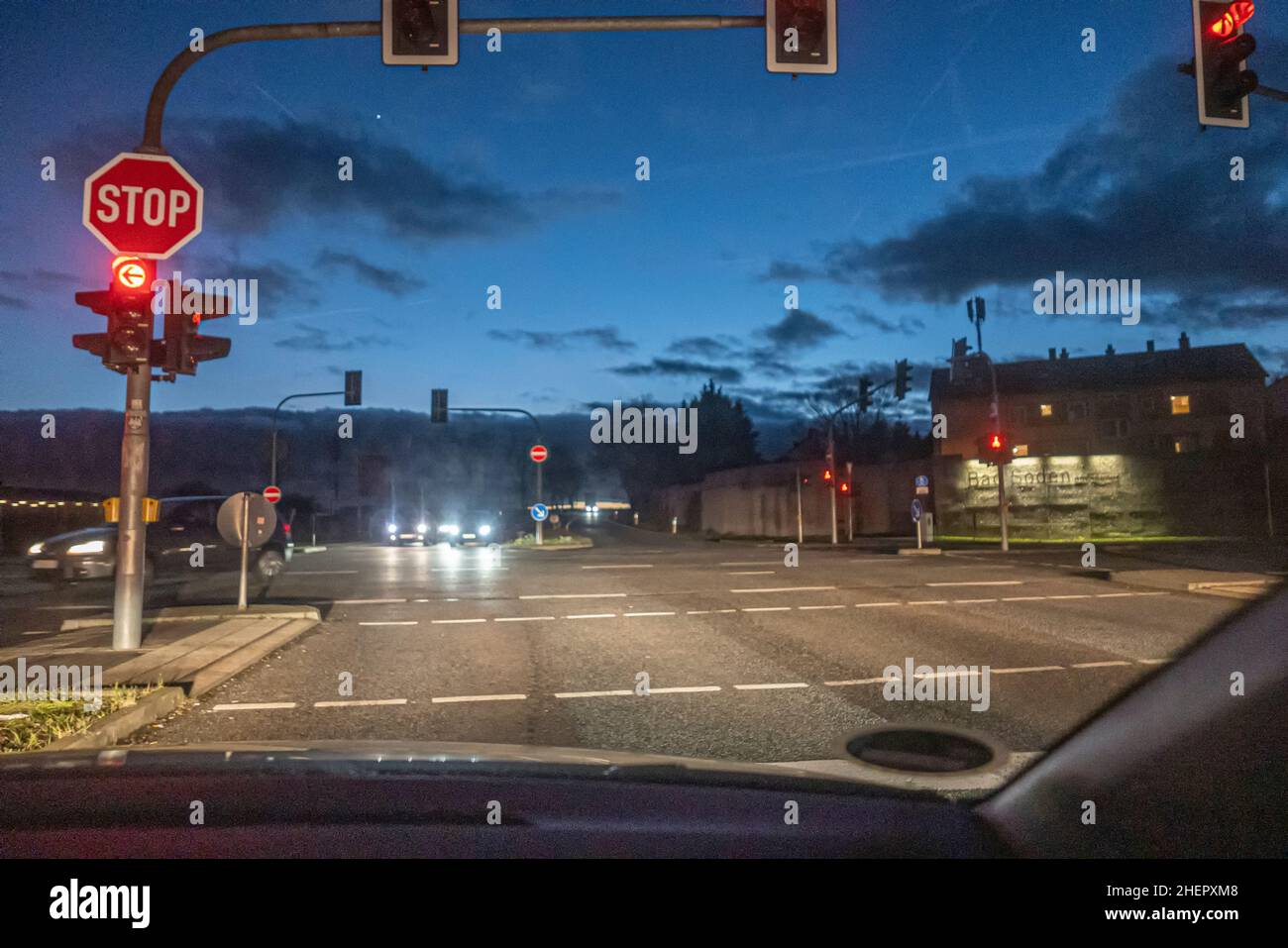 red traffic light at a crossing seen from waiting car by night in ...