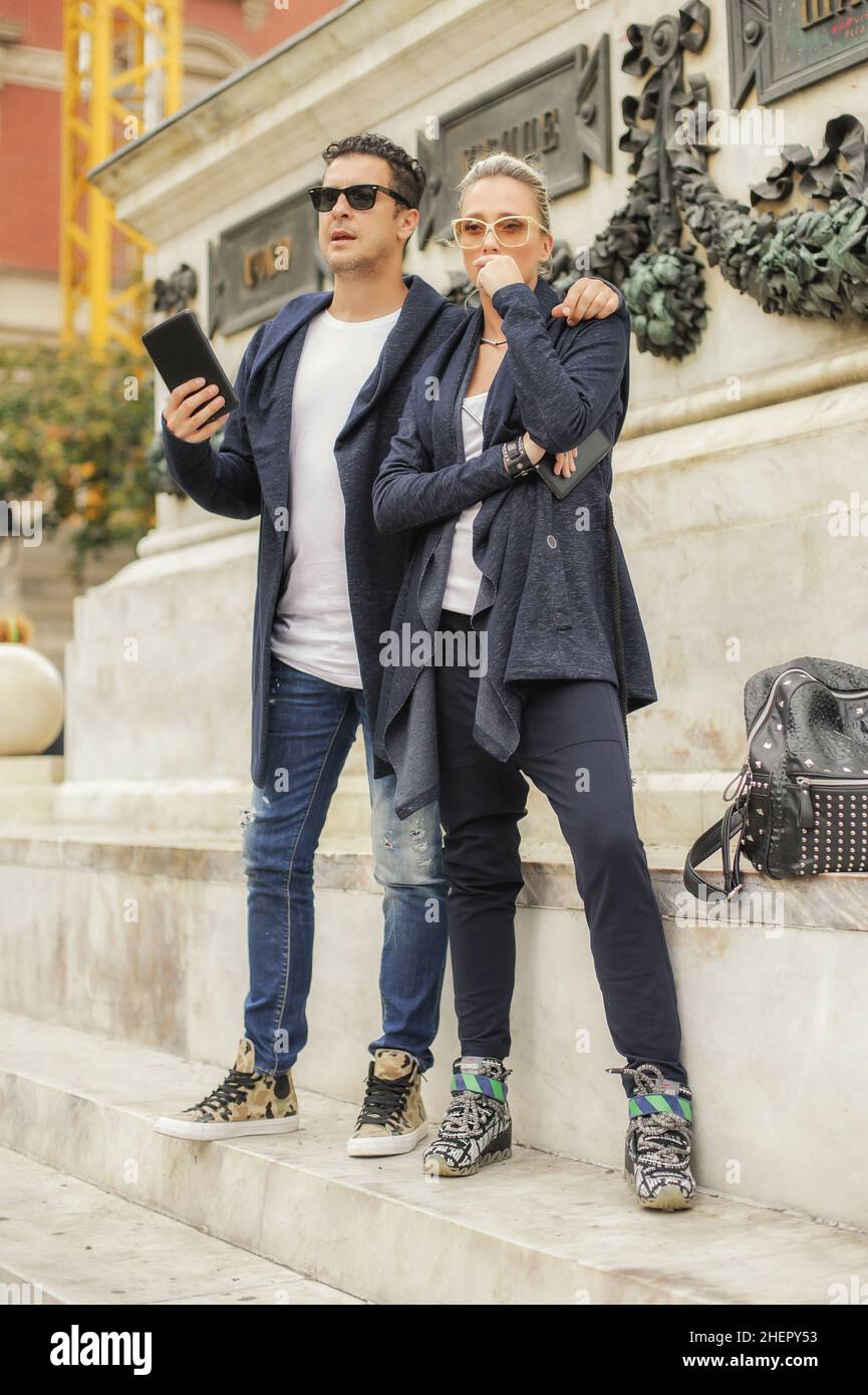 Beautiful couple sitting on steps of monument and looking at tablet ...