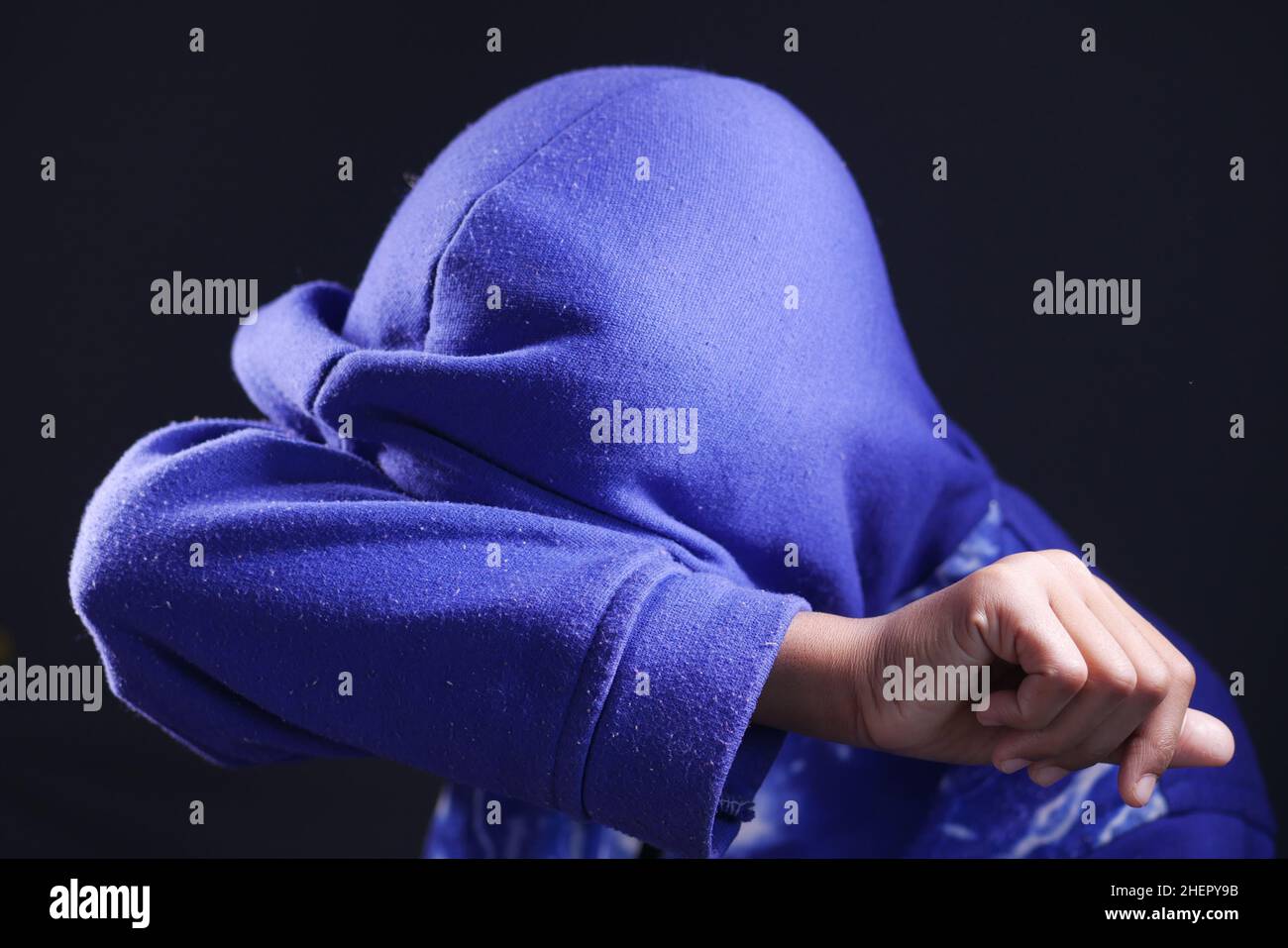 sad man in hood cover face with hands isolated in black Stock Photo - Alamy