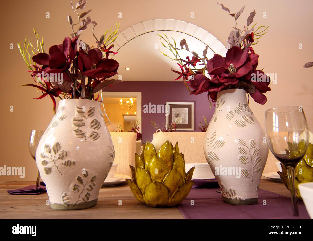 Vases with dark red flowers on a table in front of a mirror, pottery ...