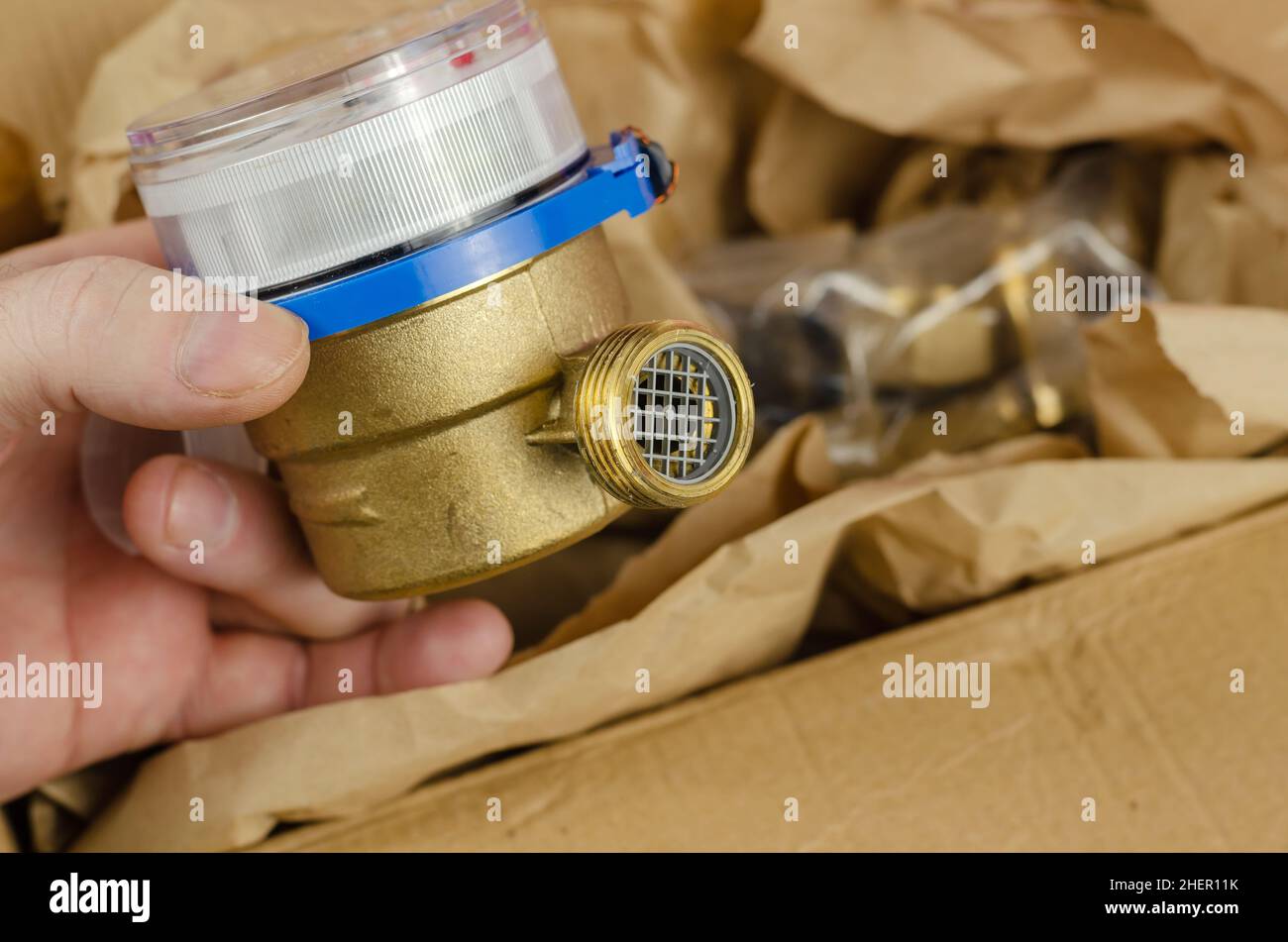 A man's hand takes a new water meter out of the box. A water meter is ...