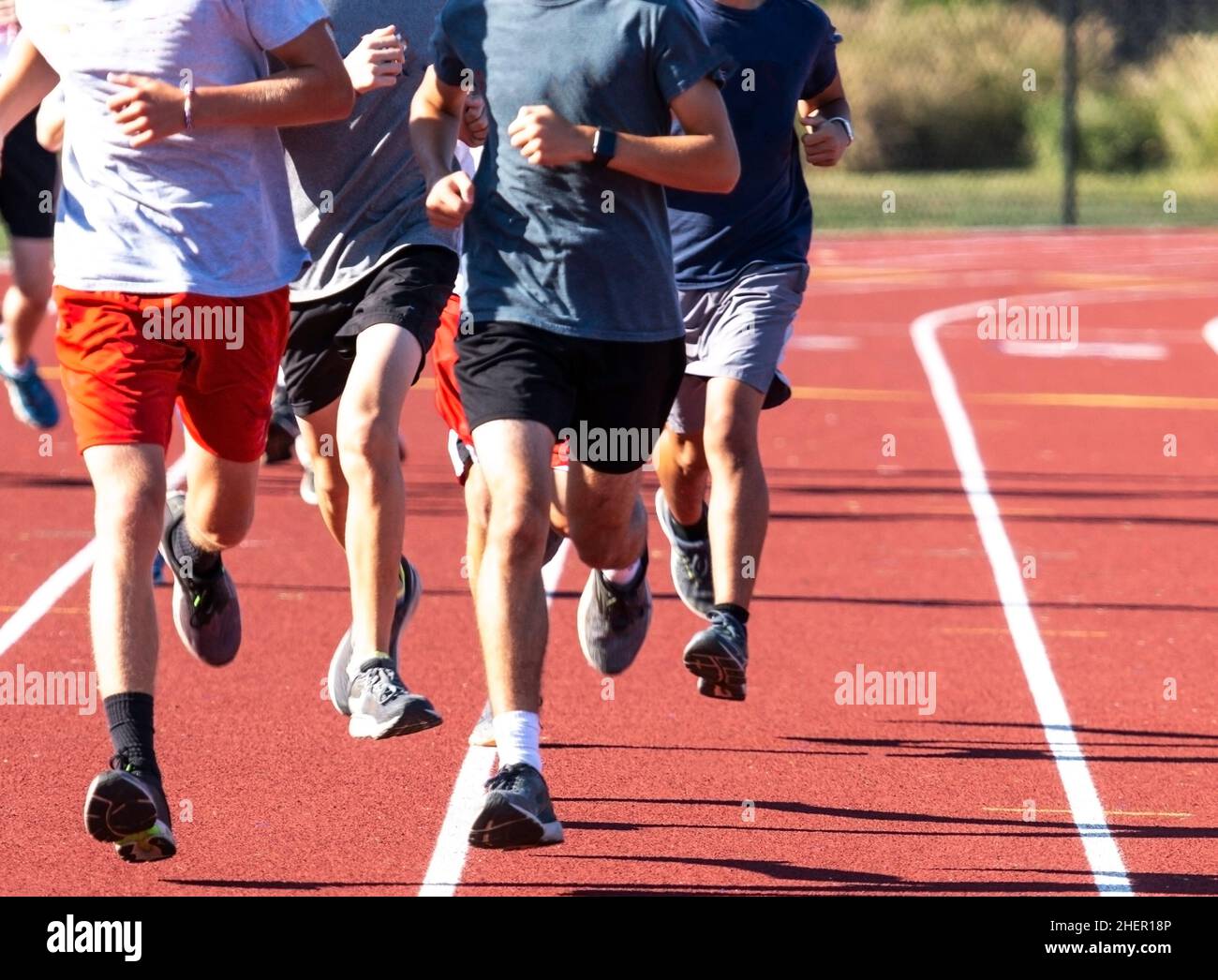 A boys high school cross country team running fast in a group on a red ...