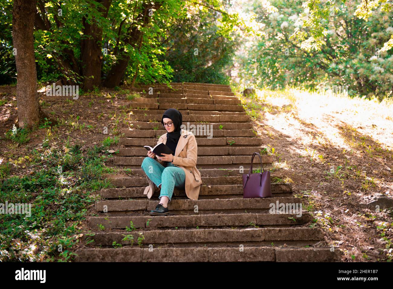 Muslim woman reading a book during springtime Stock Photo - Alamy