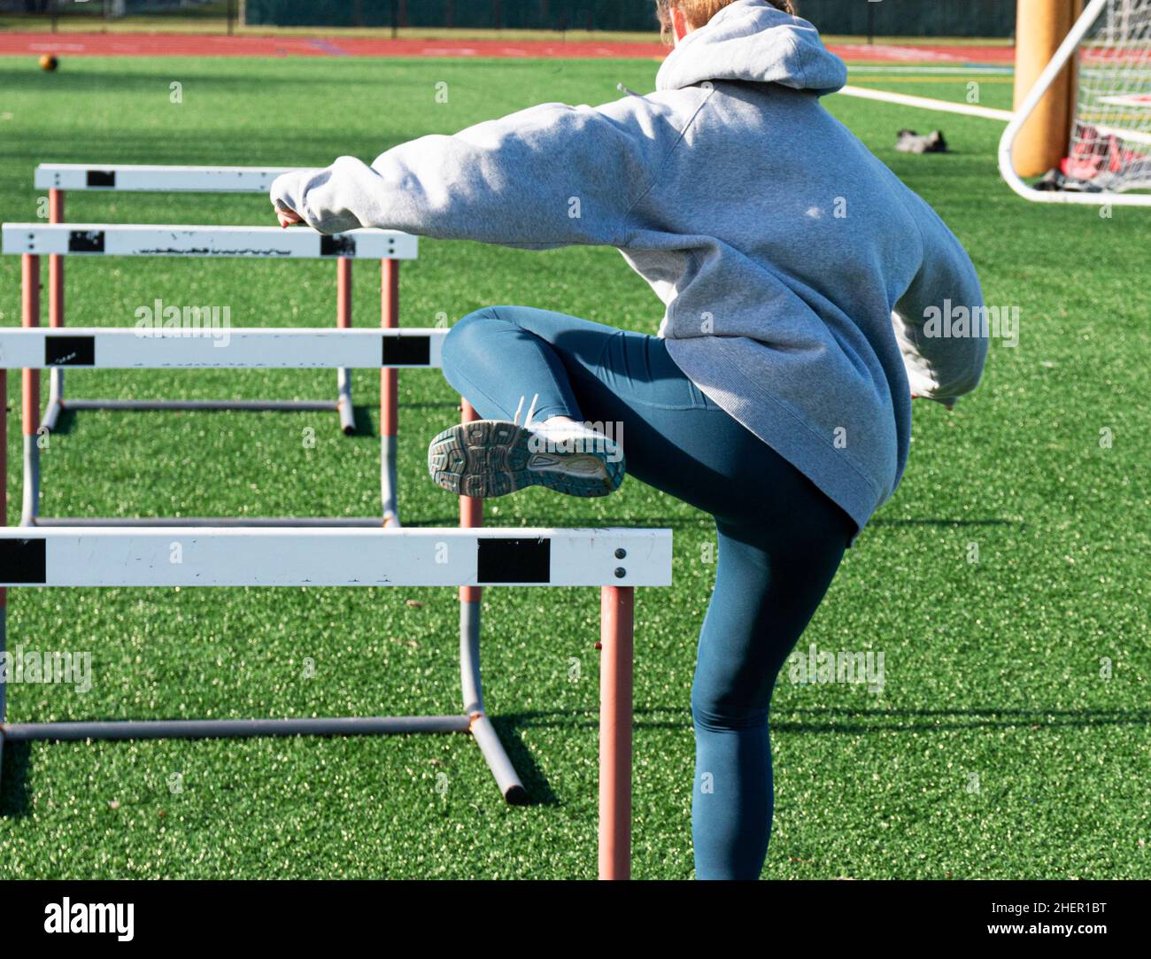 Rear view of a high school female hurdle runner performing the trail ...