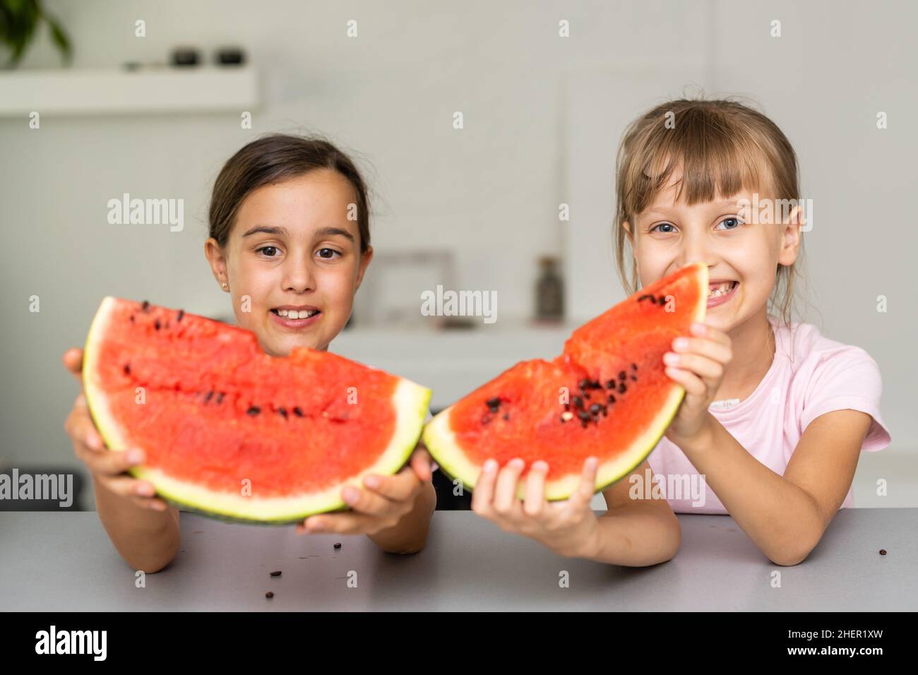 Two kids eating one slice of watermelon. Kids eat fruit outdoors ...