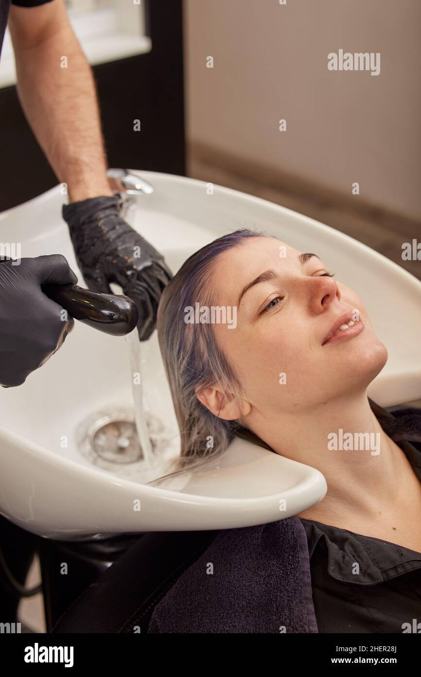Hairdresser washing toning shampoo out of woman hair Stock Photo - Alamy