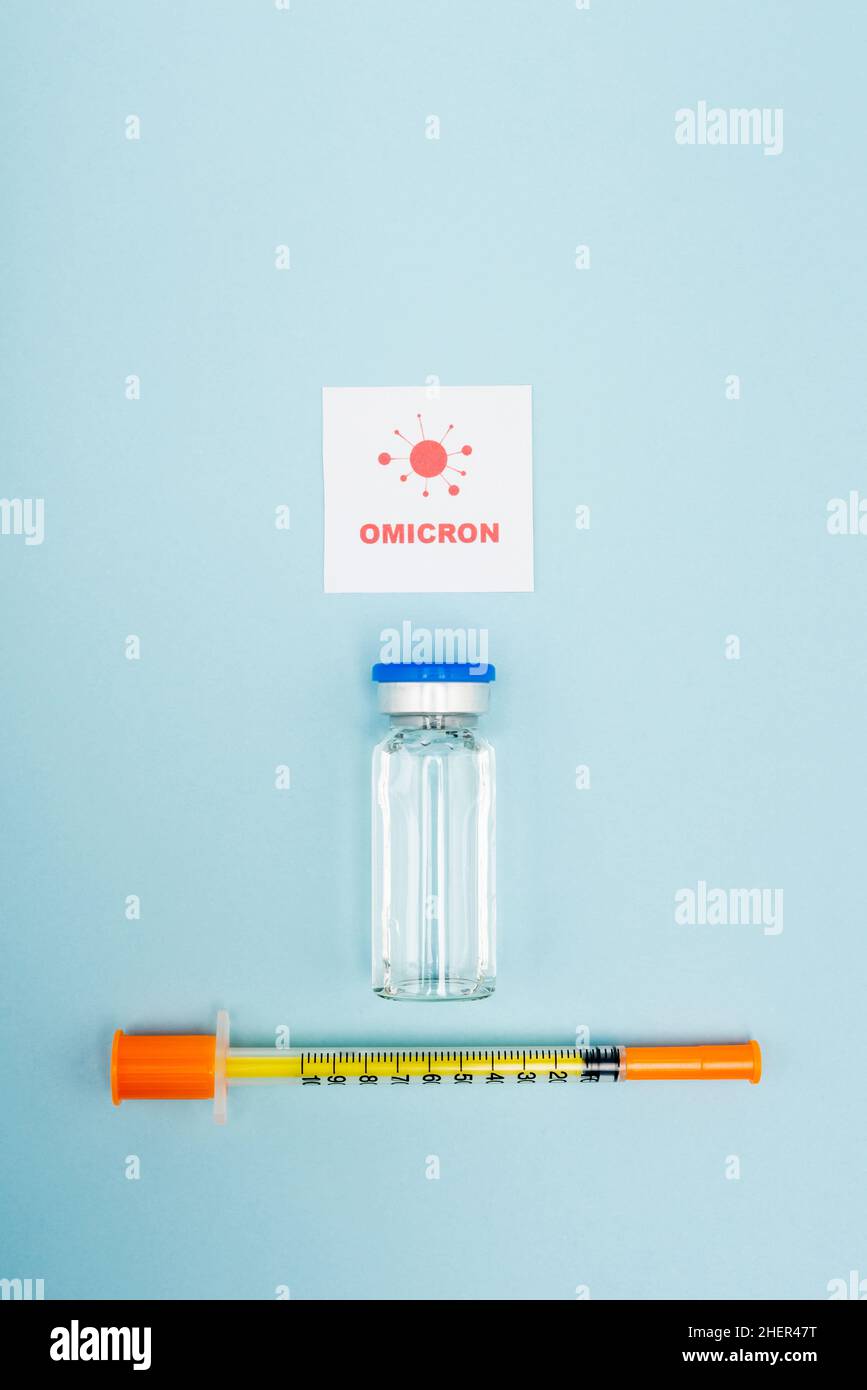top view of white card with omicron lettering and bacteria near vaccine ...
