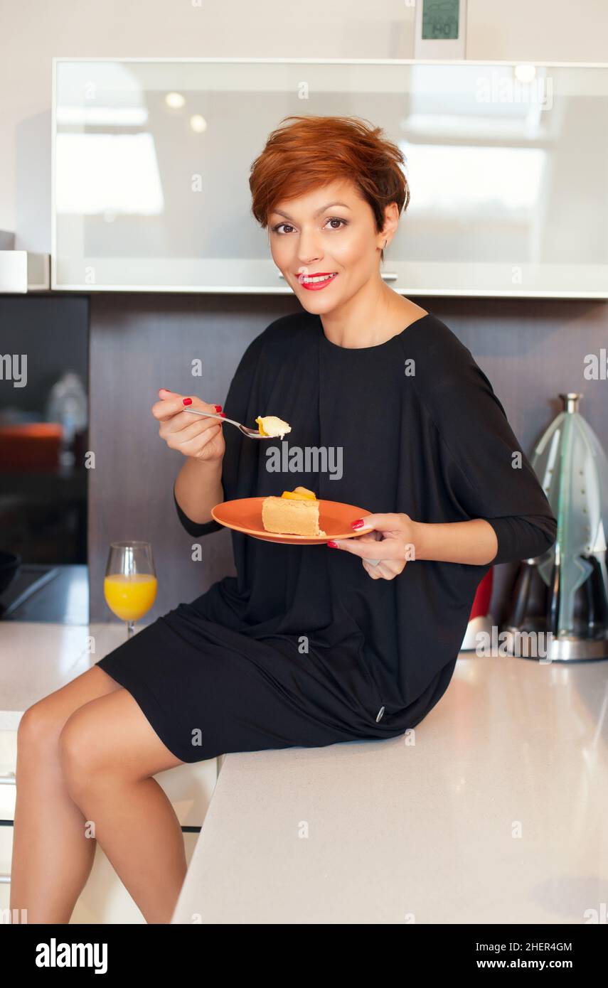 Young woman standing in kitchen and eating healthy food Stock Photo - Alamy