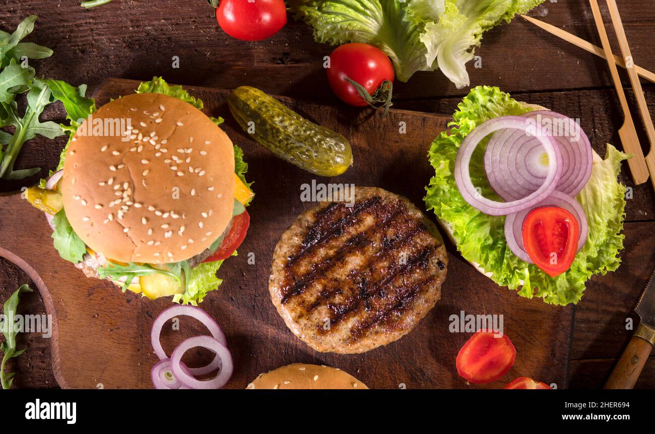 Preparation of fresh delicious burger with meatball, cheese, tomato ...