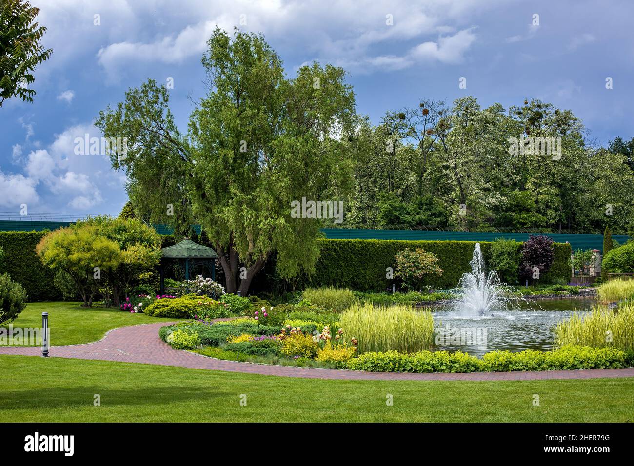 iron wrought iron gazebo with roof in park with trees and bushes by ...