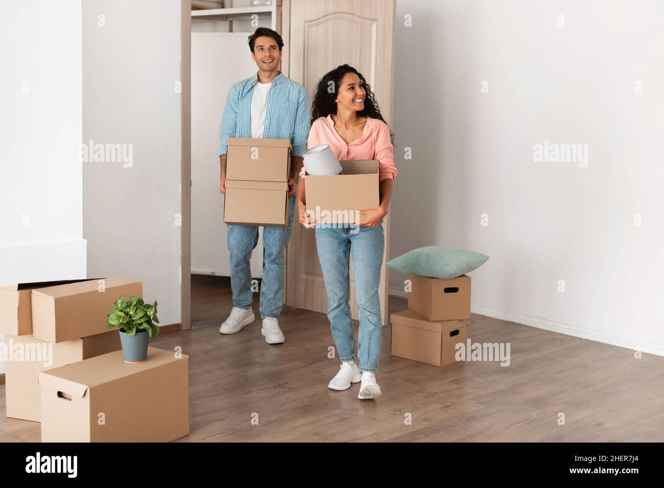 Happy couple holding cardboard boxes, walking in new house Stock Photo ...