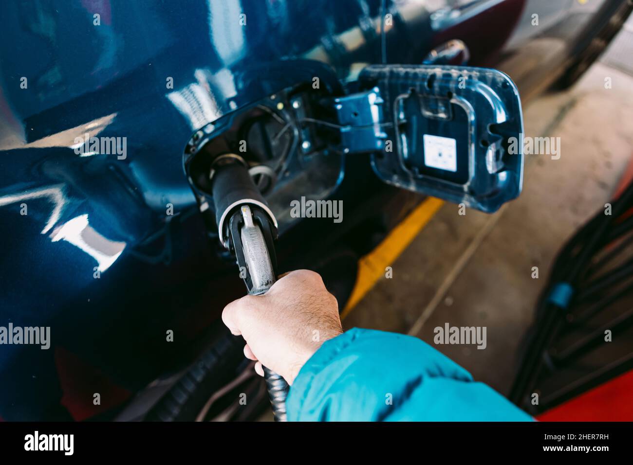 Hand holding a hose plugged into a car made of LPG (liquefied petroleum ...