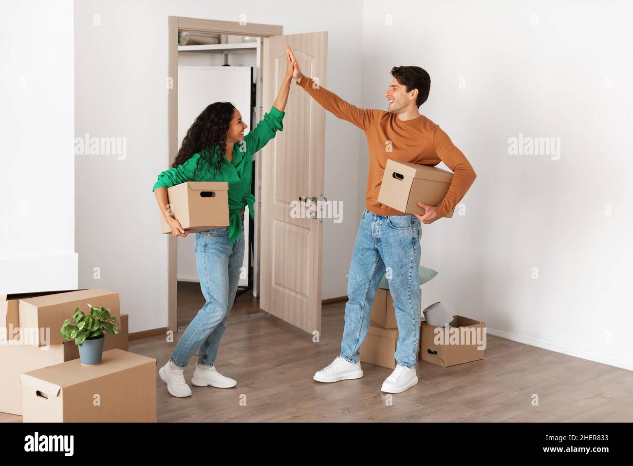 Happy man and woman giving high five celebrating moving day Stock Photo ...