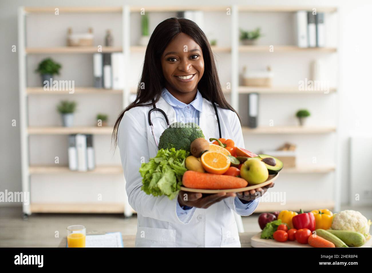 Choose quality healthy food. Happy black nutritionist holding bowl of ...