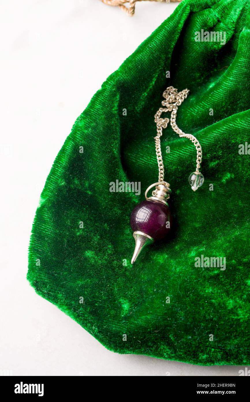 Natural stone pendulum on green velvet, Reiki concept Stock Photo - Alamy
