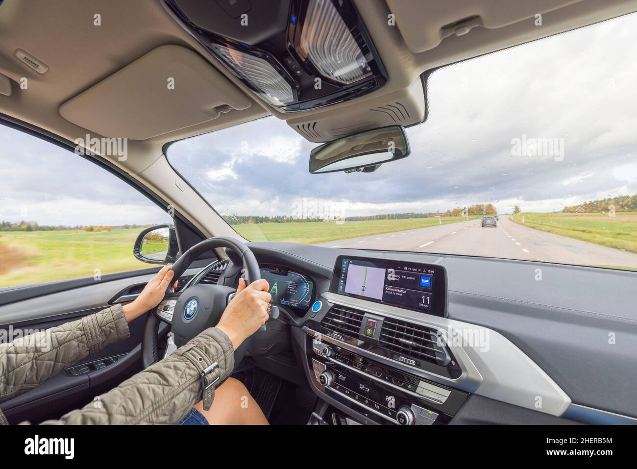 Beautiful interior view of BMW iX3 on road. Female driver in vehicle ...