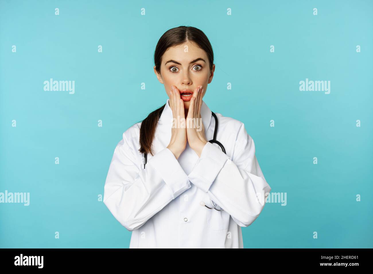 Portrait of shocked woman doctor, female hospital intern in white coat ...