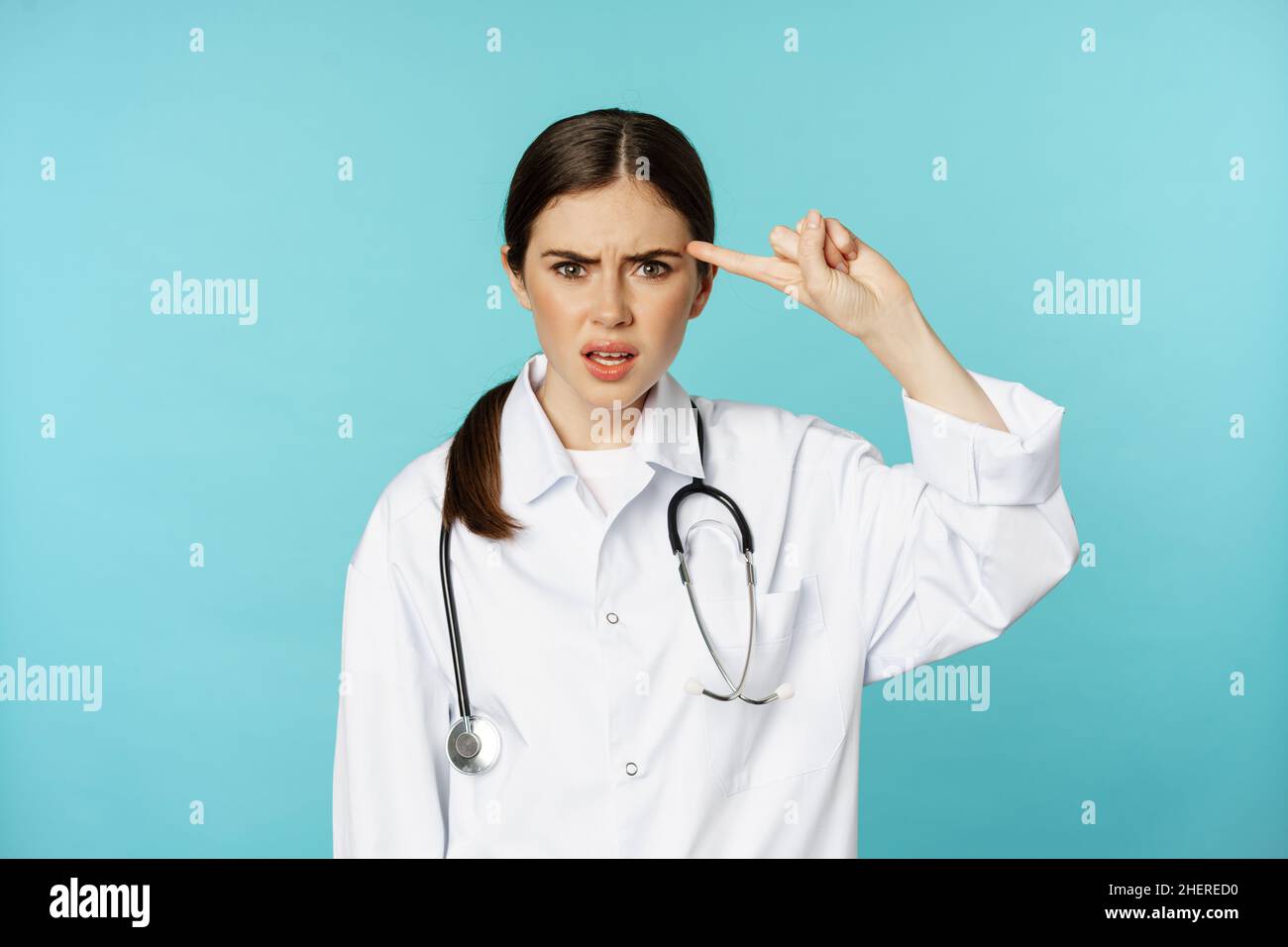 Annoyed woman doctor pointing finger at head, scolding someone stupid ...