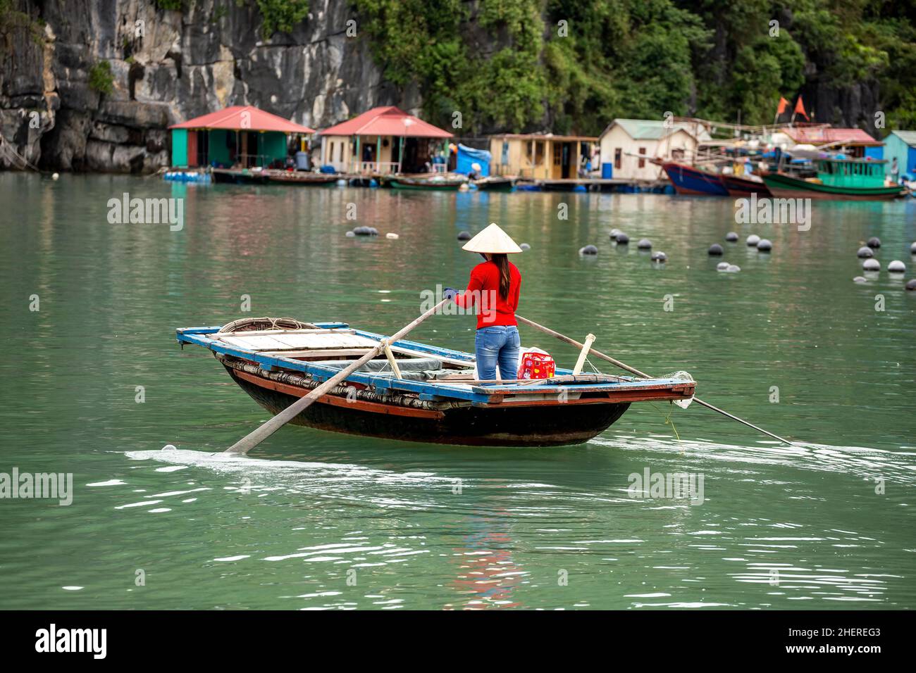 Woman rowing wooden rowboat and floating houses, Vung Vieng fishing ...