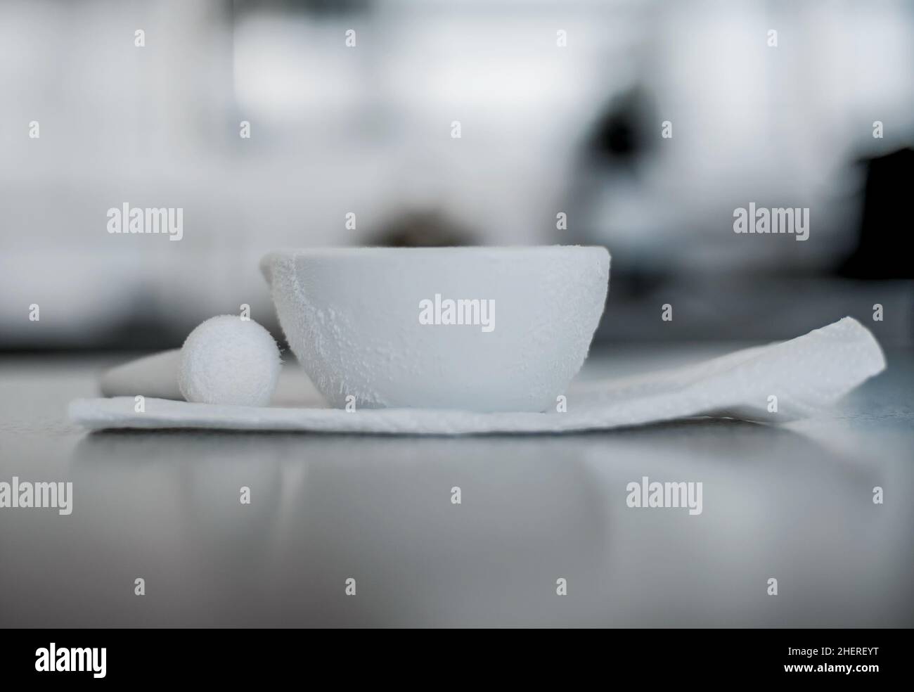 Frozen laboratory mortar with pestle after experiment with liquid ...