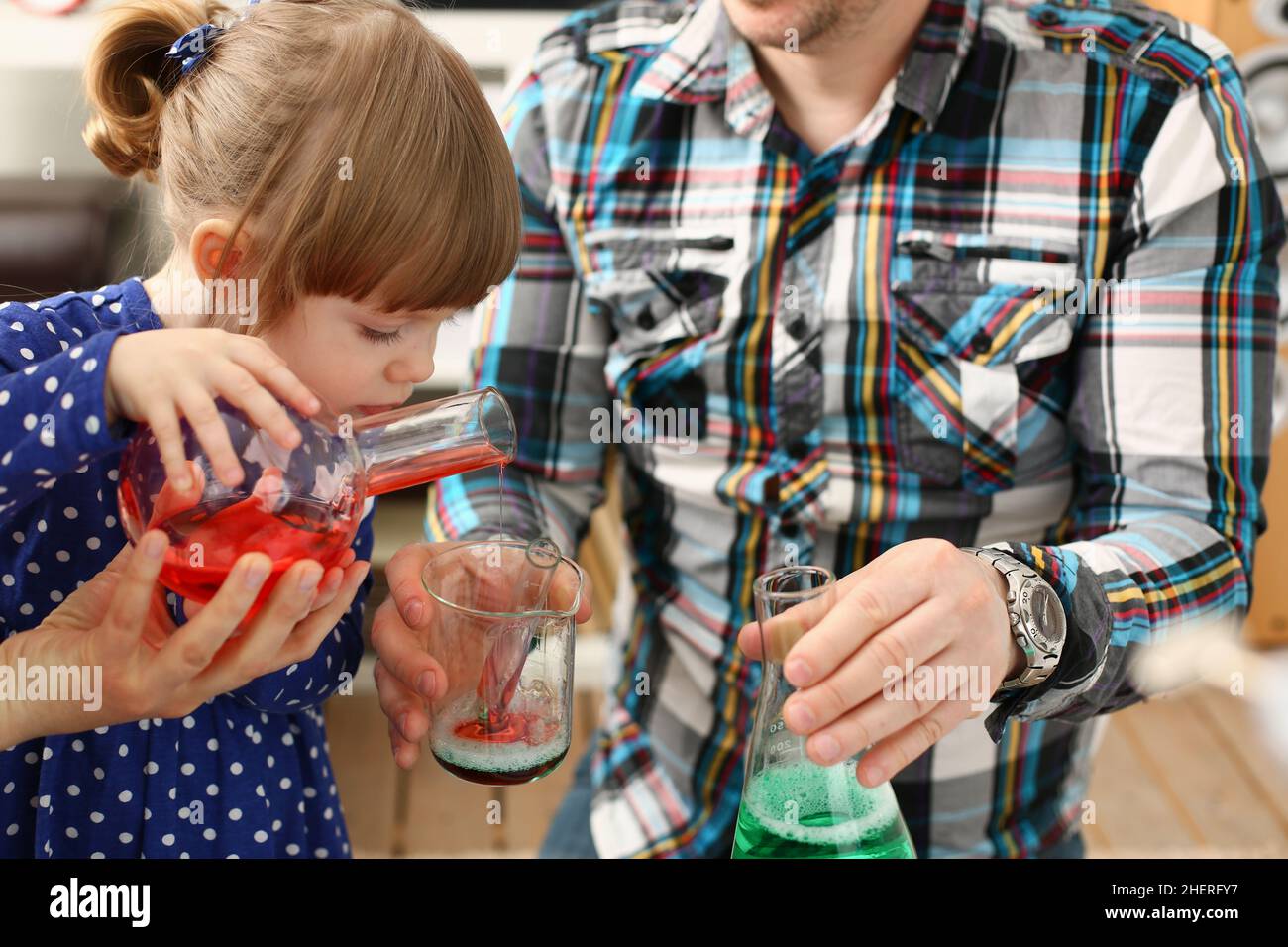 Man and little girl are playing colorful liquids in flasks Stock Photo ...