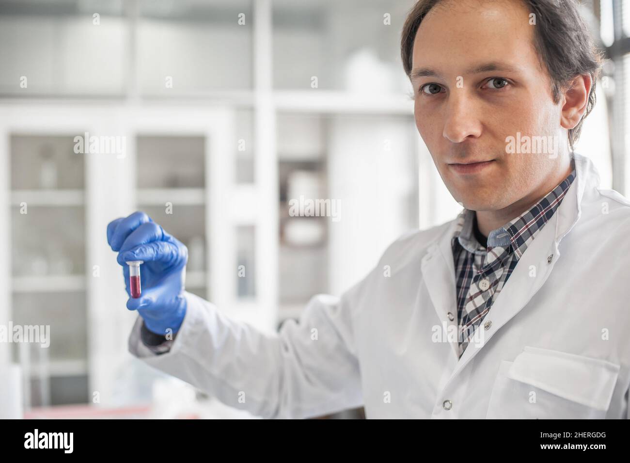 Male lab technician holding a test tube with sample in the medical or ...