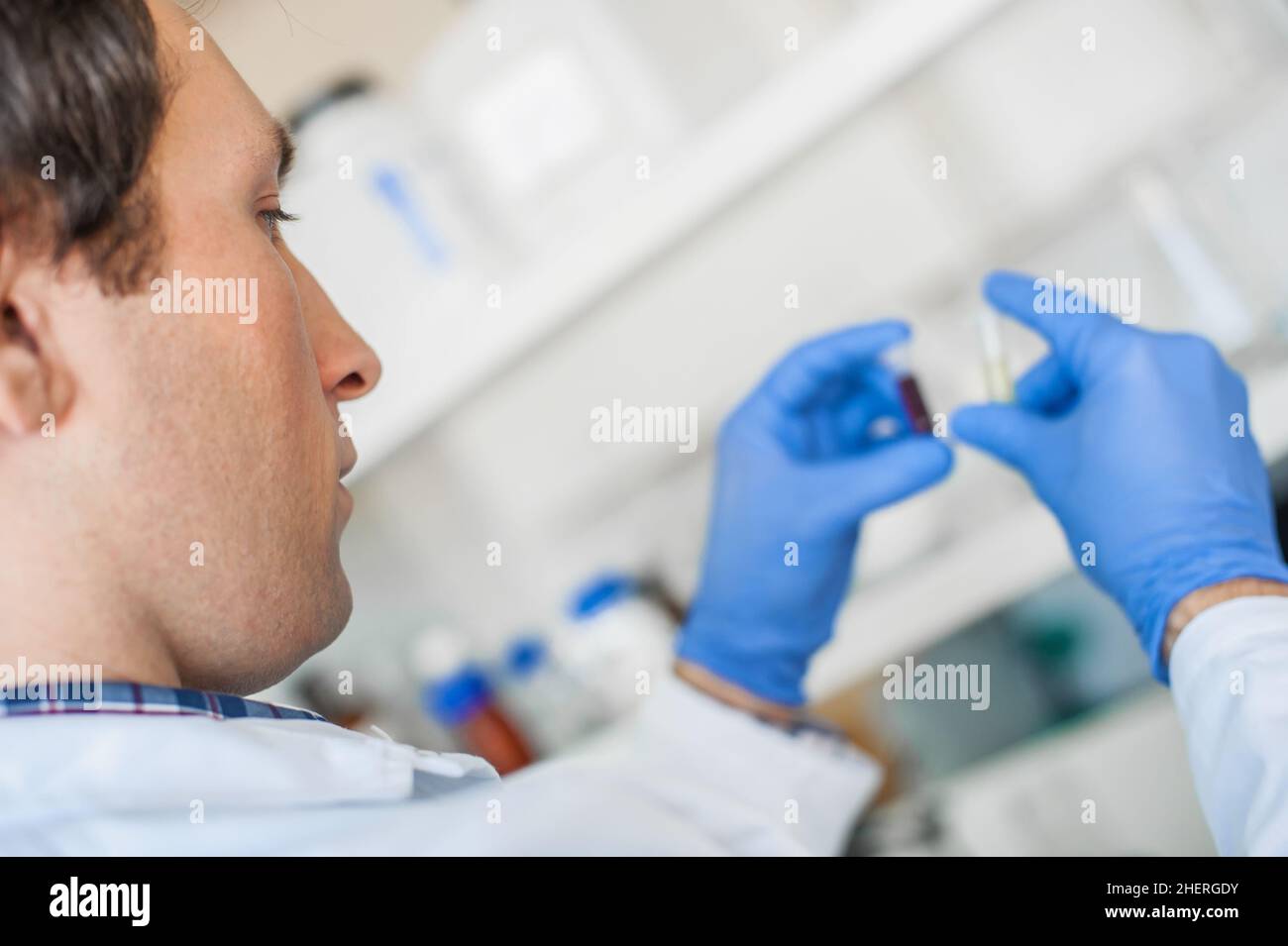 Male lab technician holding a test tube with sample in the medical or ...