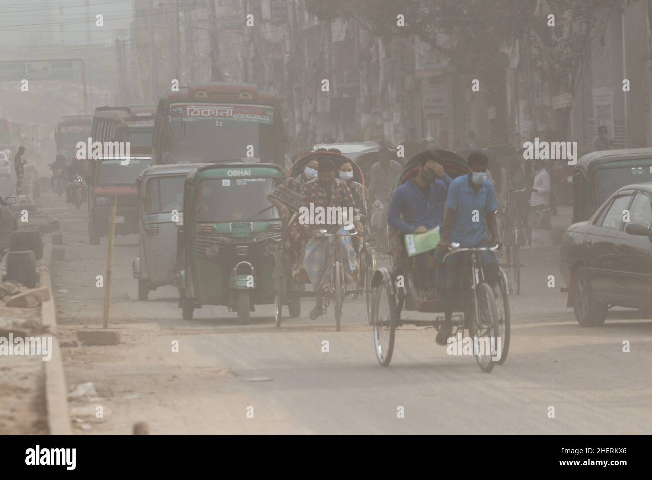 Vehicles and motorcycles crossing a dusty road. Dust pollution reaches ...