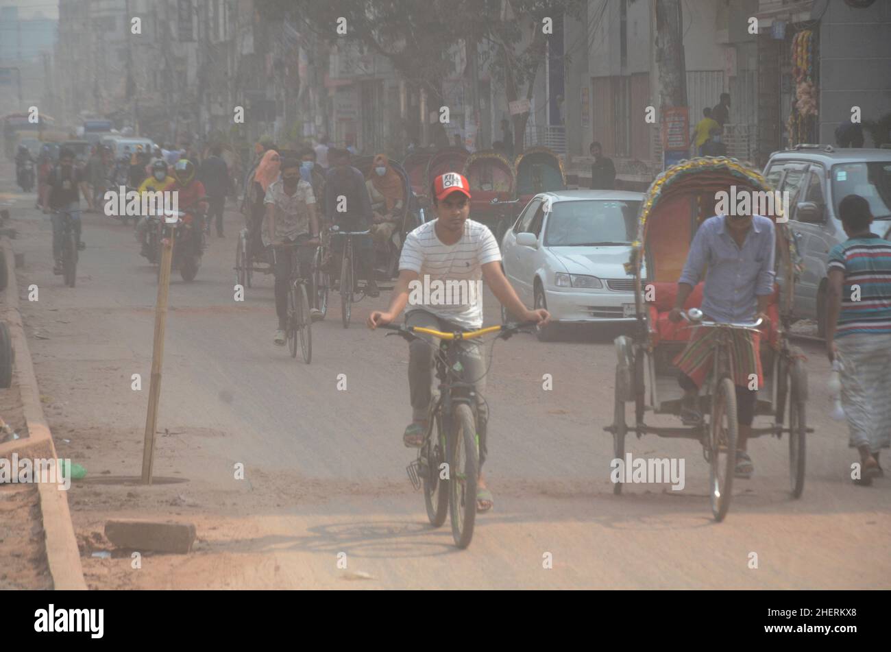 Vehicles and motorcycles crossing a dusty road. Dust pollution reaches ...