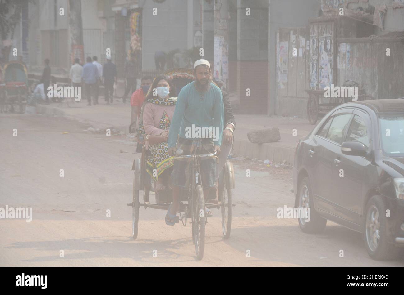Vehicles and motorcycles crossing a dusty road. Dust pollution reaches ...
