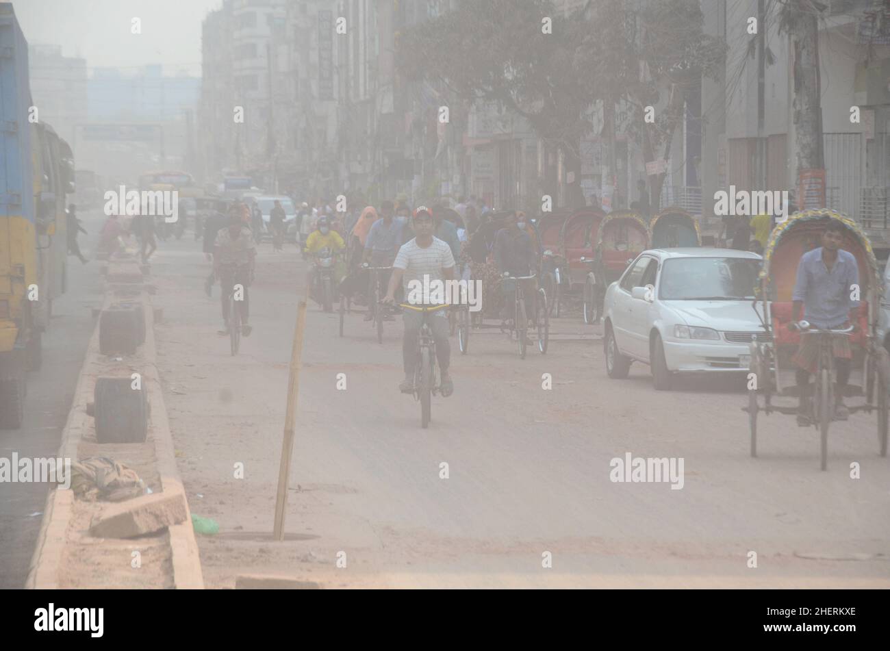 Vehicles and motorcycles crossing a dusty road. Dust pollution reaches ...