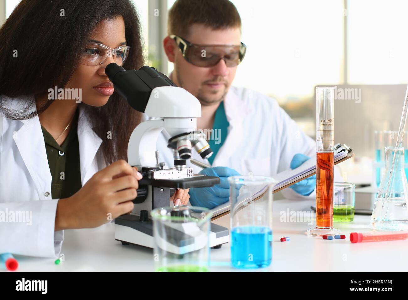 Two chemistry students conduct microscopic examinations in laboratory ...
